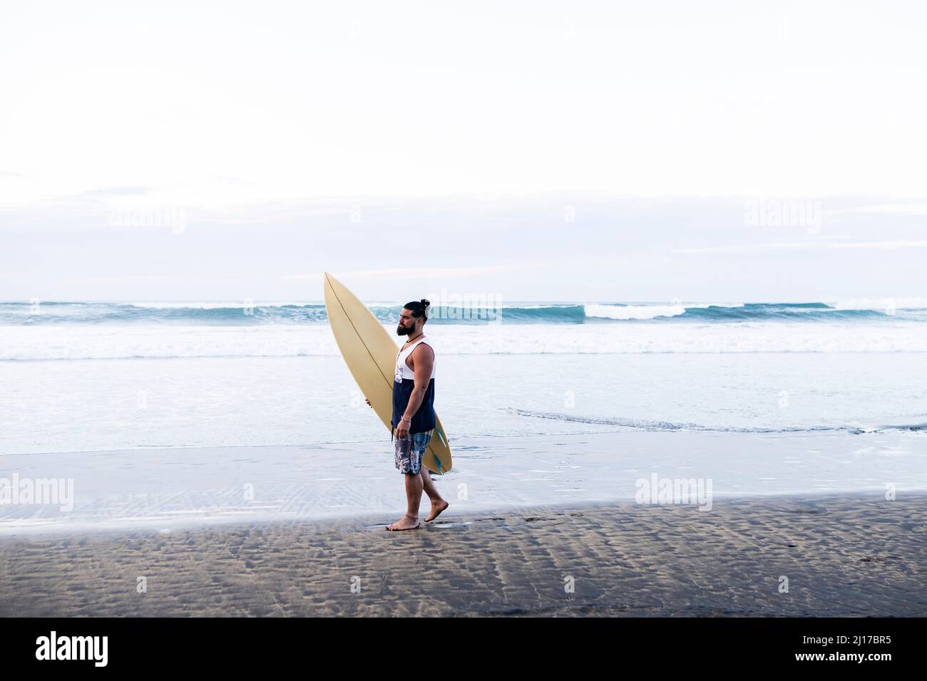 Man carrying surfboard walking at beach Stock Photo - Alamy