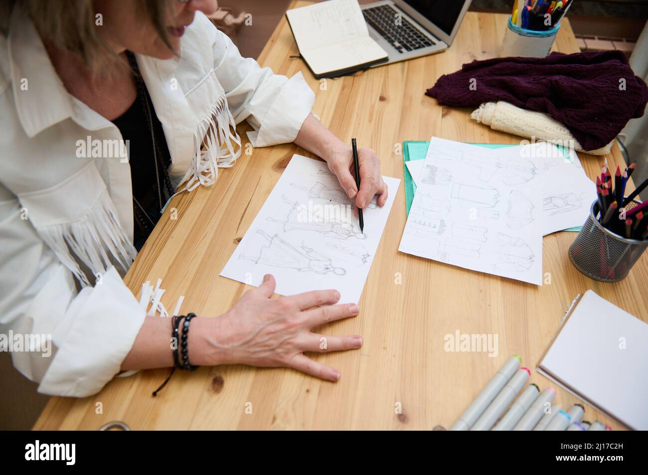 Close-up elderly inspired fashion designer drawing sketch of new ...
