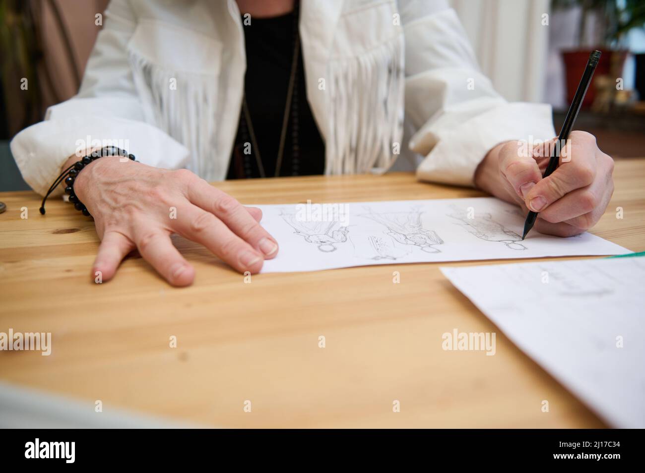 Focus on the hand of a fashion designer holding a pencil and drawing ...