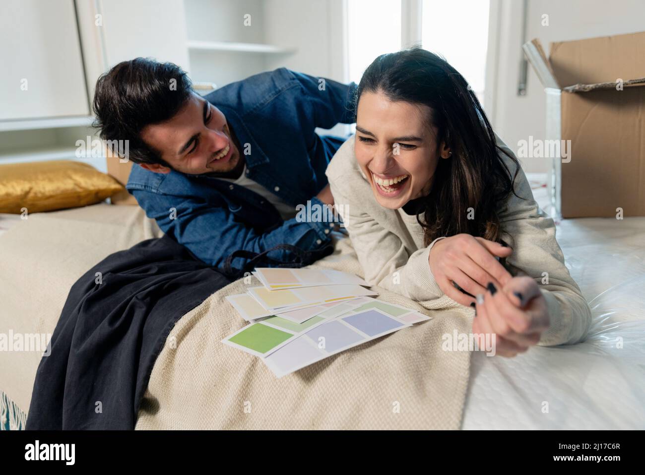 Cheerful young couple choosing color swatches in bedroom at new home ...