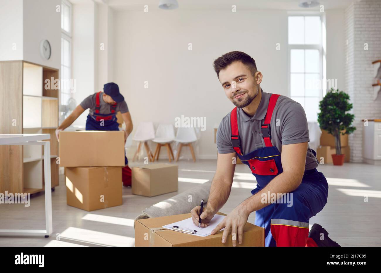 Moving service workers pack cardboard boxes and checking list in client ...