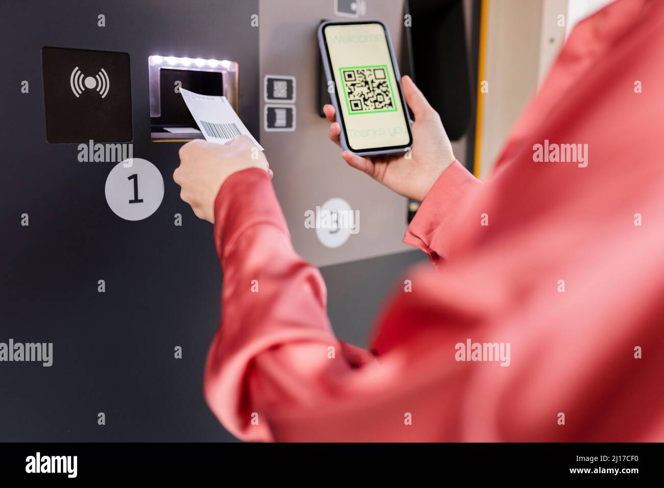 Woman scanning QR code on ticket machine through smart phone at station ...