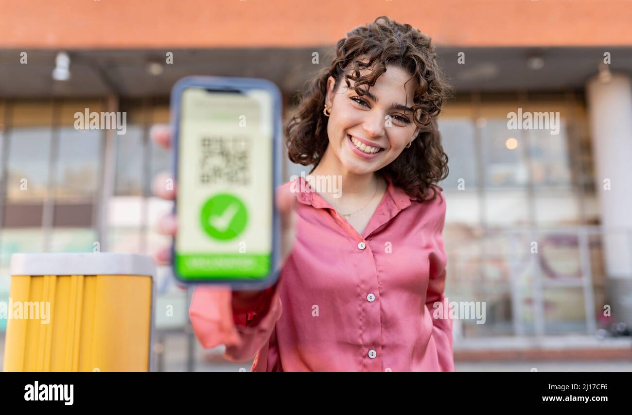 Smiling woman showing QR code over smart phone Stock Photo - Alamy