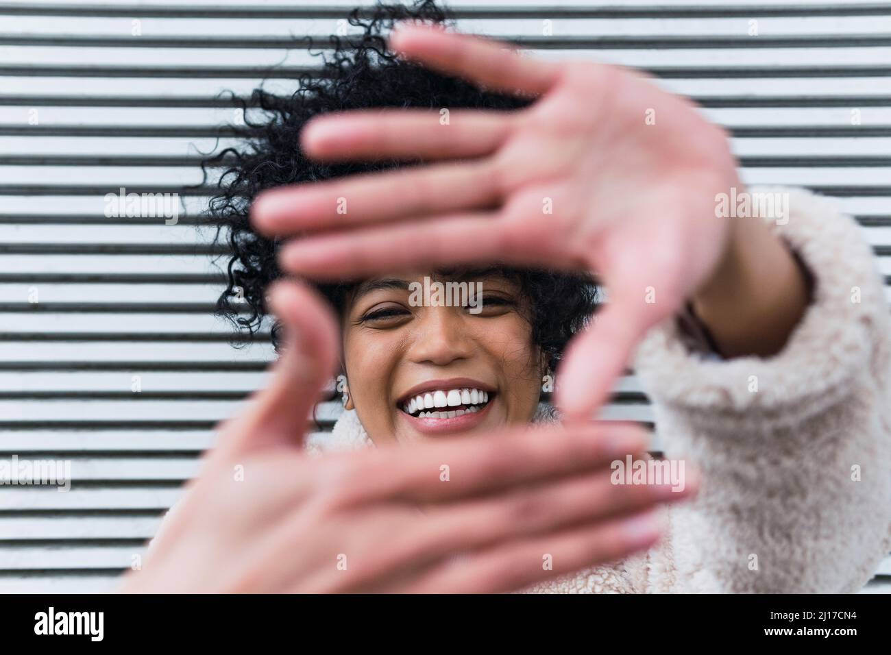 Happy woman making finger frame in front of striped wall Stock Photo ...