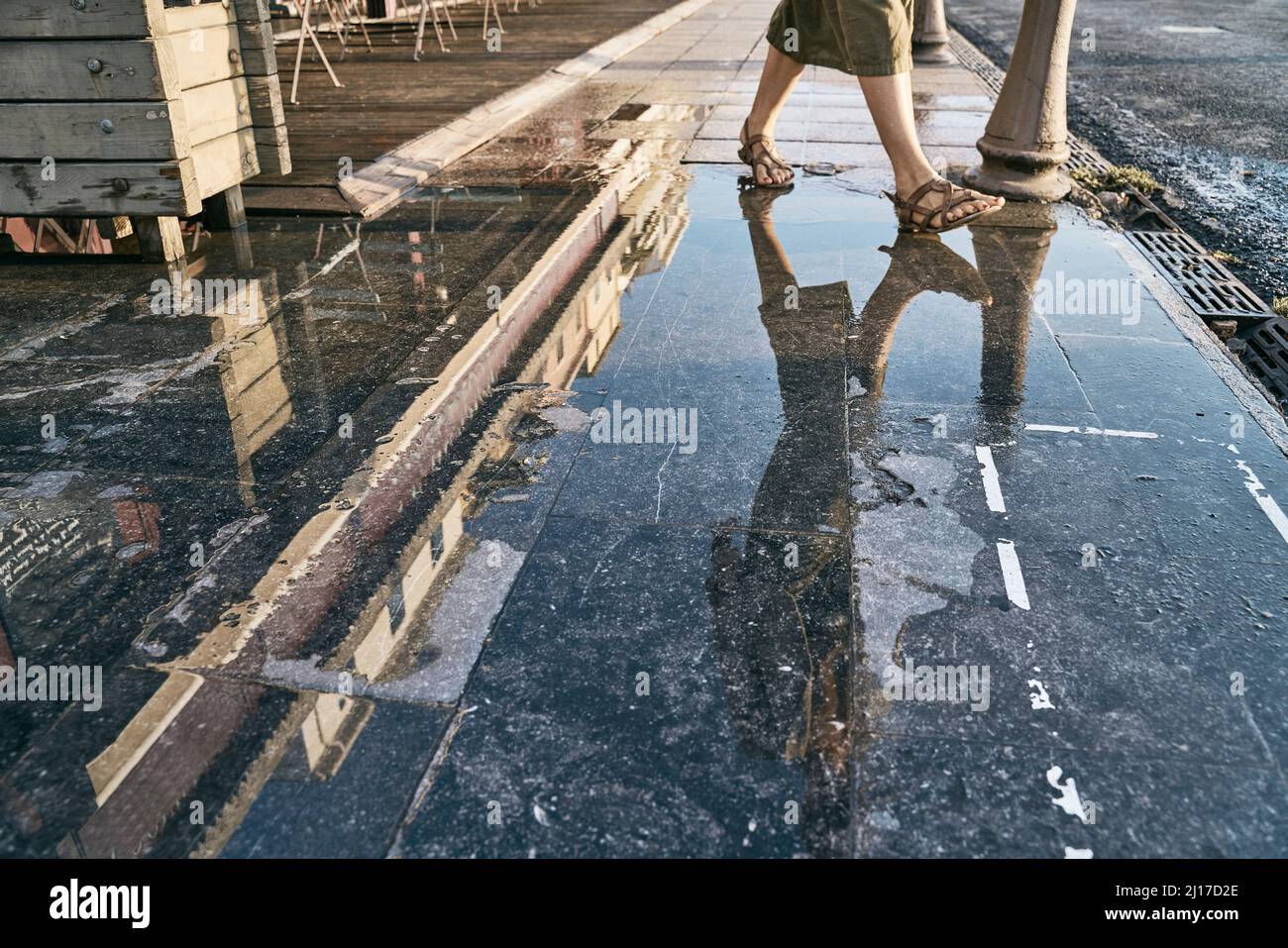Woman walking through puddle at sidewalk Stock Photo - Alamy