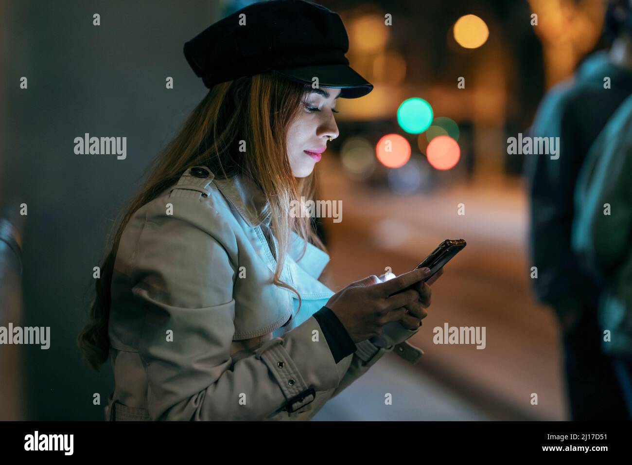 Woman wearing cap using mobile phone at night Stock Photo - Alamy