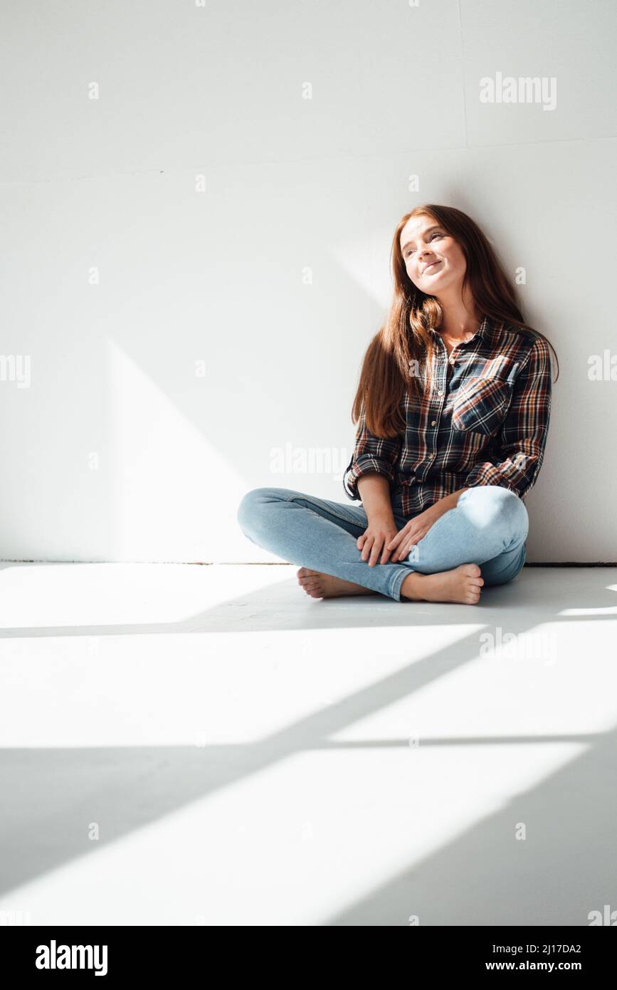 Contemplative woman sitting in front of white wall Stock Photo - Alamy
