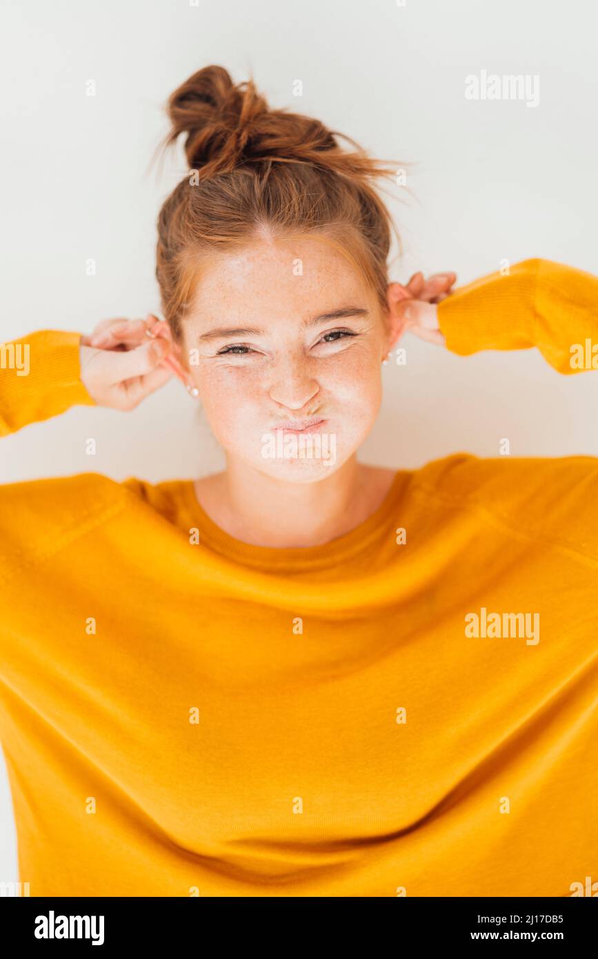Young woman pulling ears against white background Stock Photo - Alamy