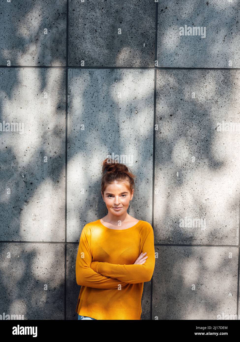 Confident woman with arms crossed in front of wall Stock Photo - Alamy