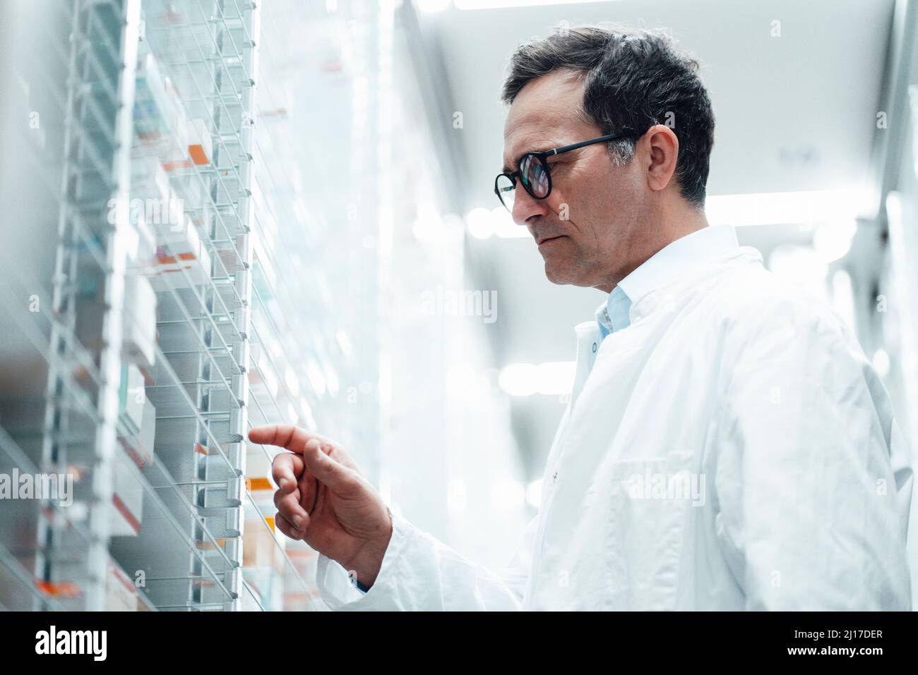 Pharmacist checking medicines on shelf in pharmacy Stock Photo - Alamy