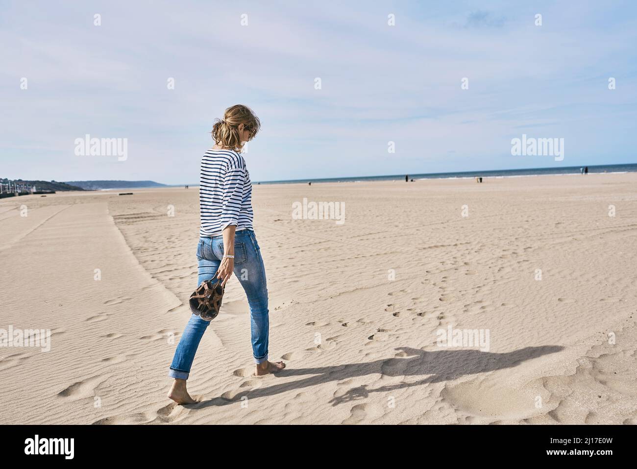 Woman walking on sand at beach Stock Photo - Alamy