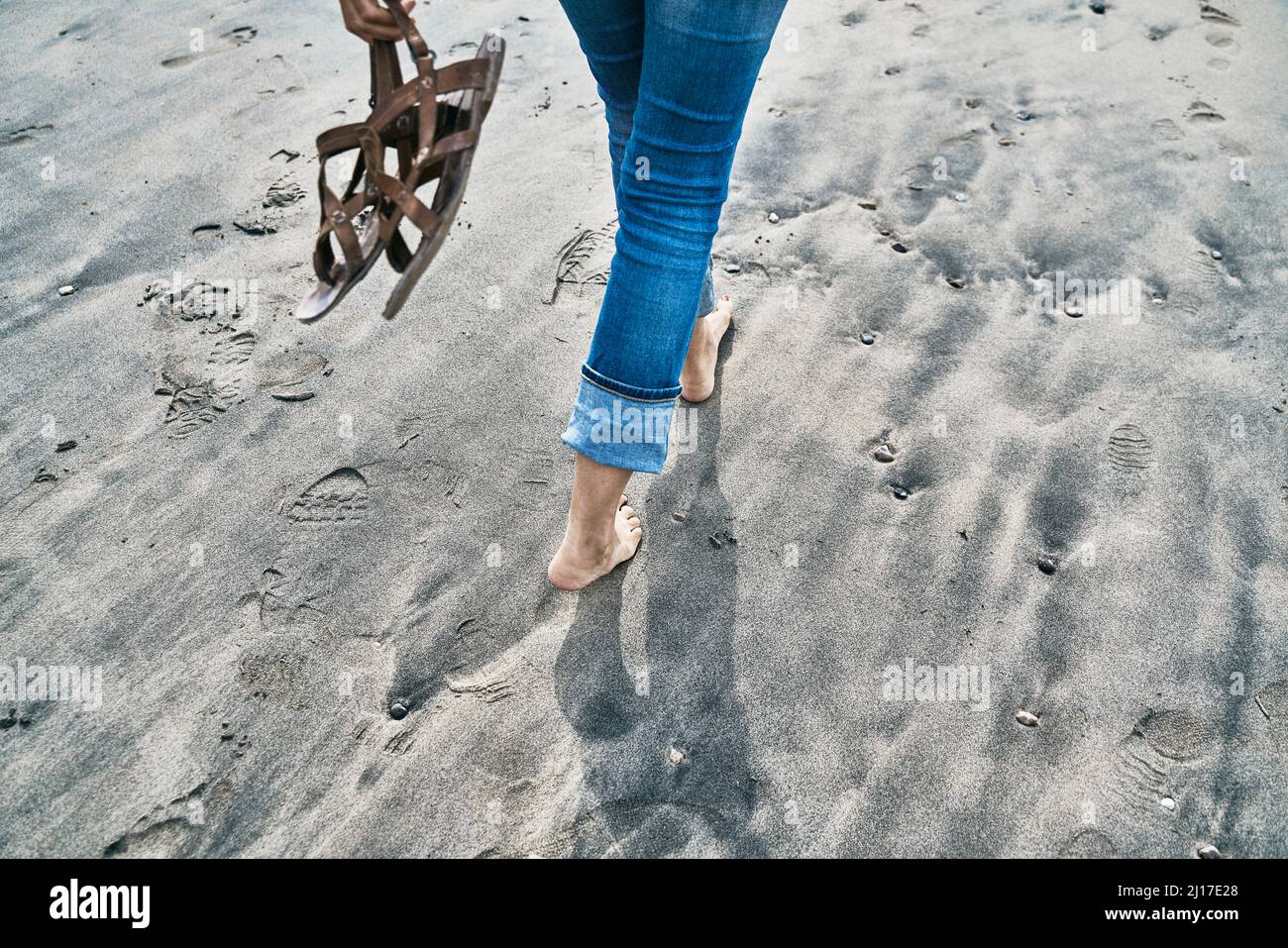 Tourist walking barefoot on wet sand Stock Photo - Alamy