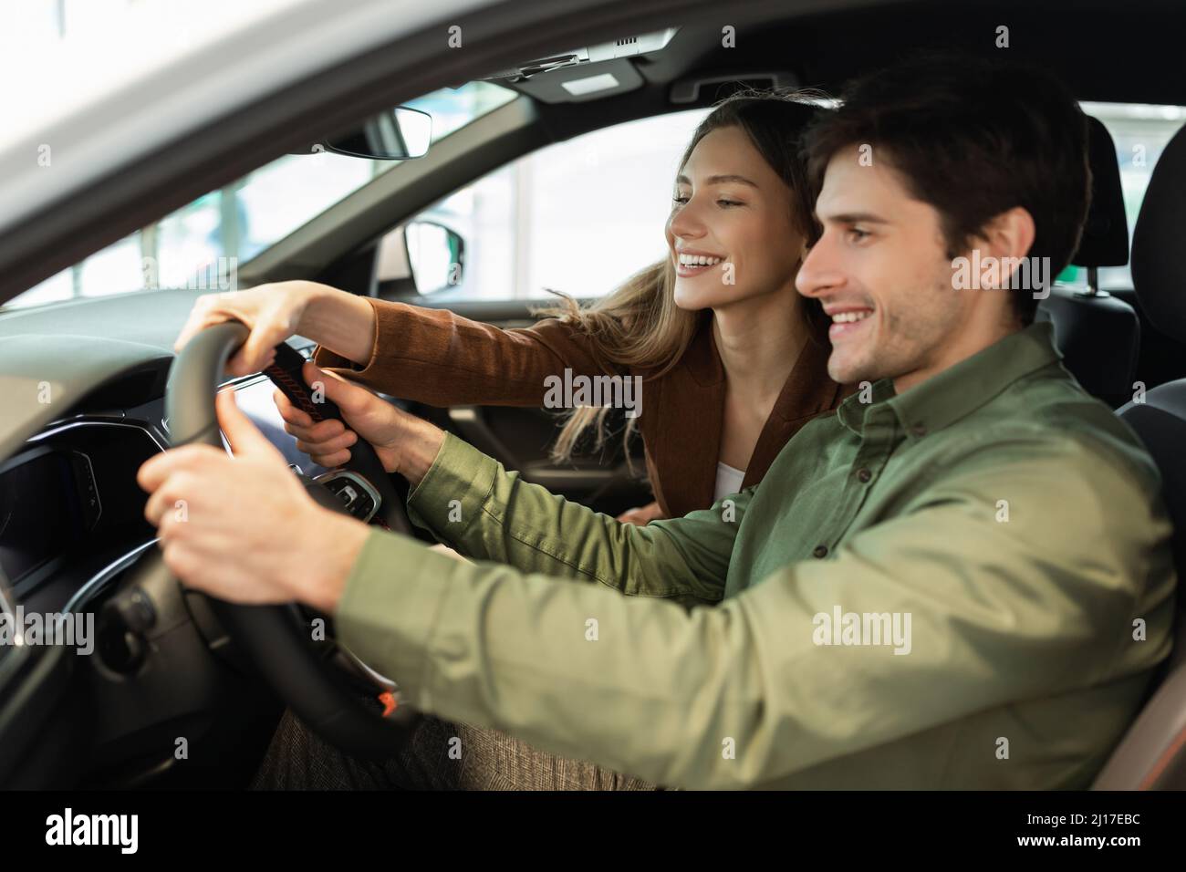 Happy young couple test driving new car at modern auto dealership Stock ...
