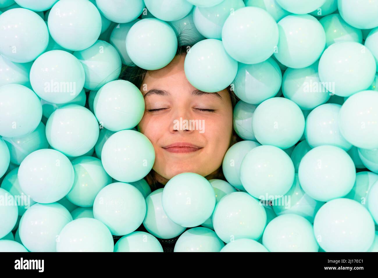 Smiling woman with eyes closed amidst blue balls Stock Photo - Alamy