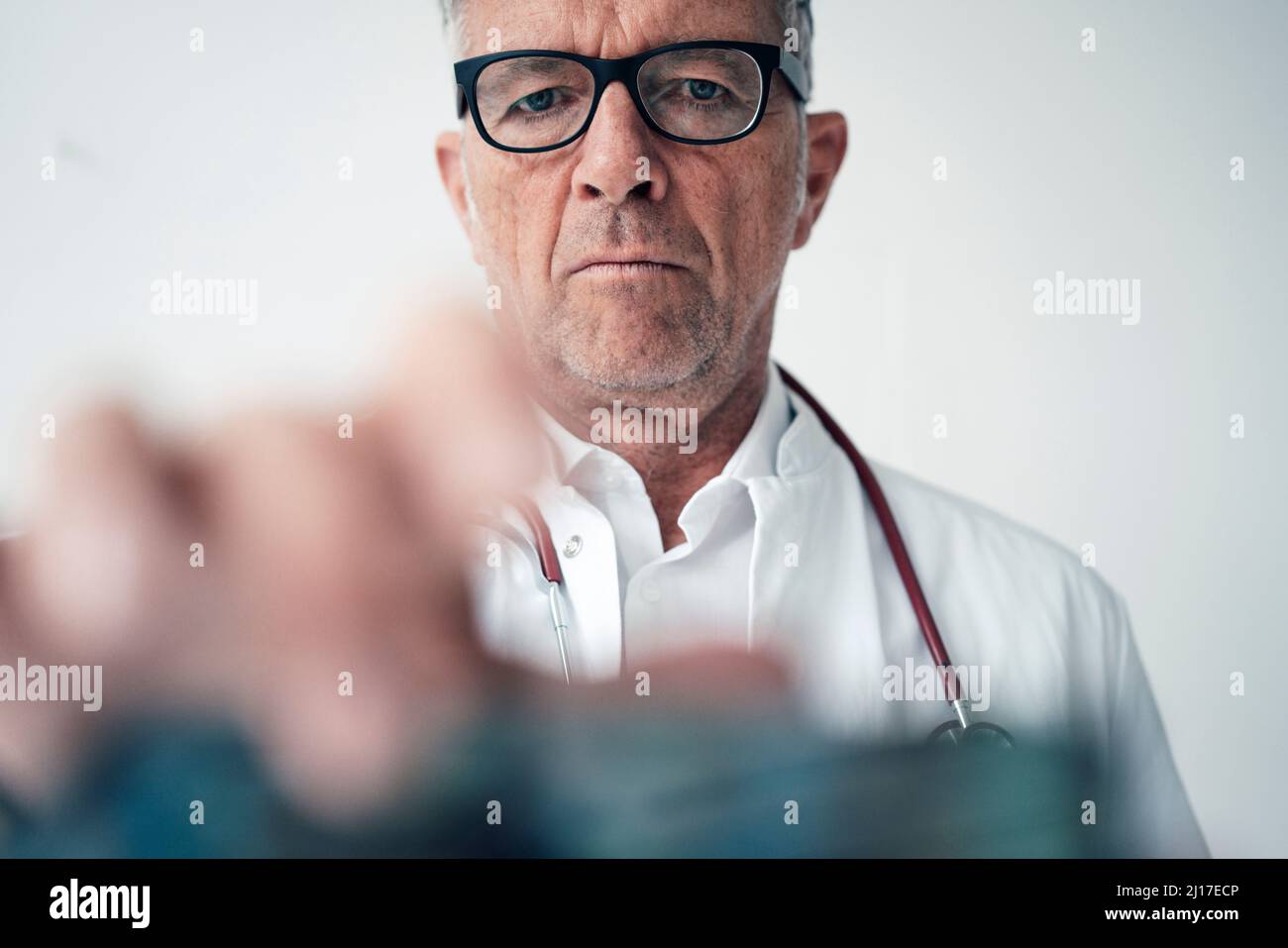 Doctor using medical equipment in front of wall Stock Photo - Alamy
