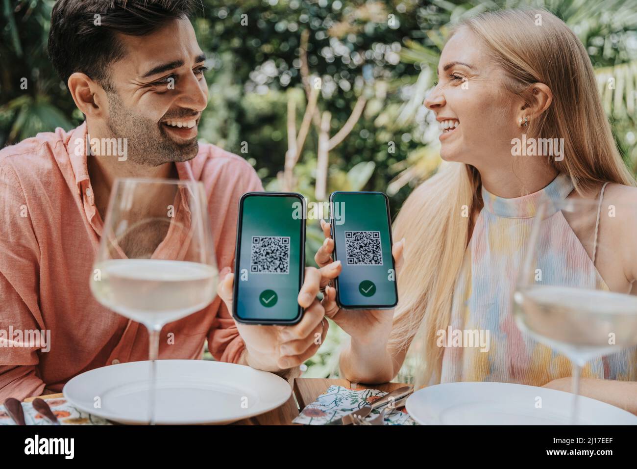 Happy couple showing QR codes on smart phones at restaurant Stock Photo ...
