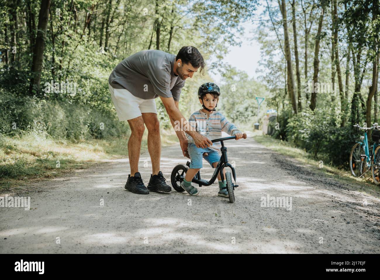 Father teaching son to ride cycle on road Stock Photo - Alamy