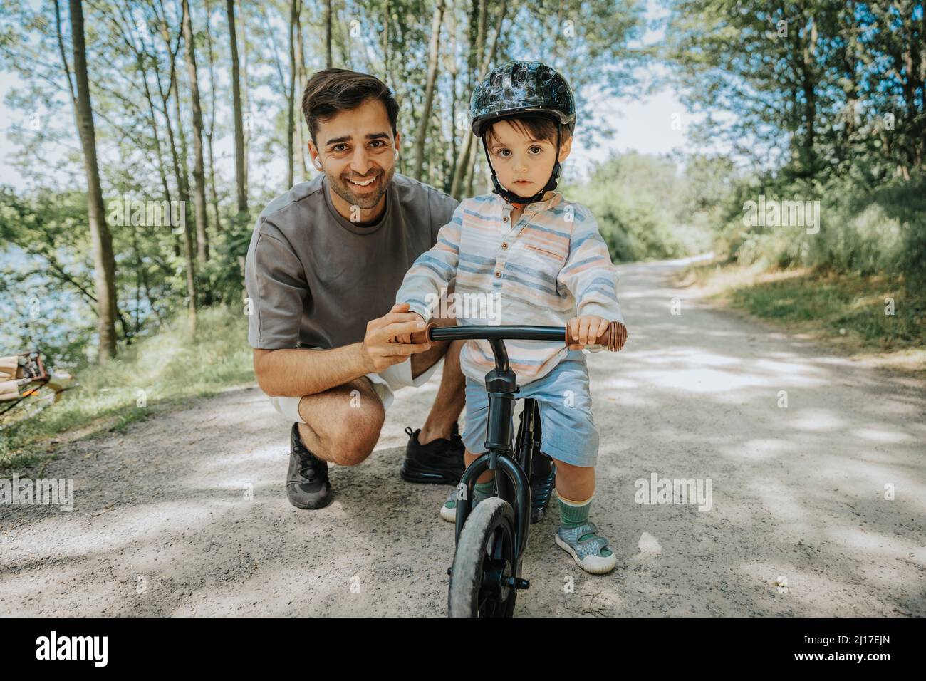 Smiling father and son with cycle on road Stock Photo - Alamy