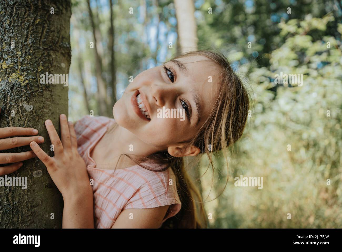 Smiling girl hugging tree in nature Stock Photo - Alamy