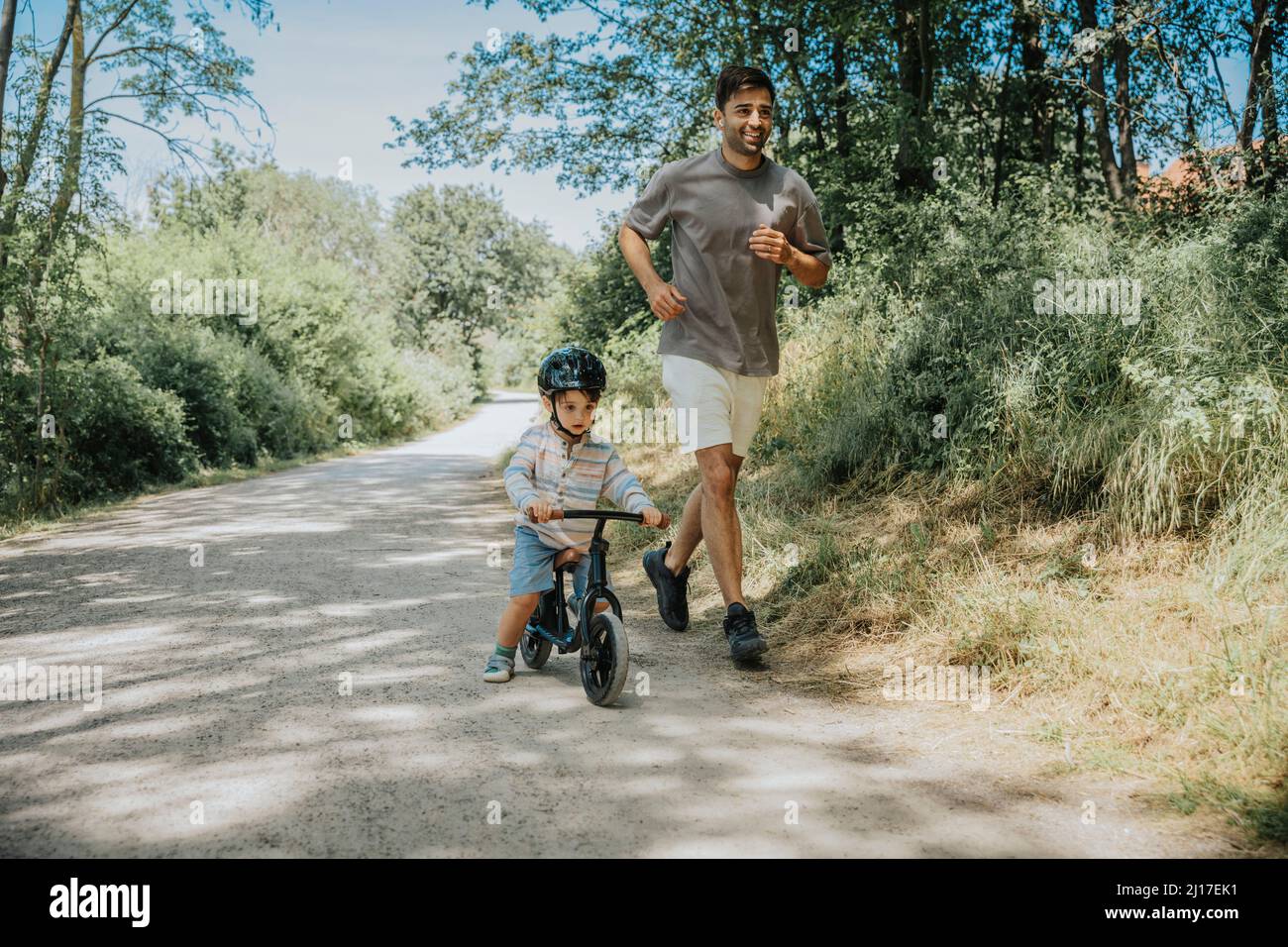 Father running by son cycling on road Stock Photo - Alamy