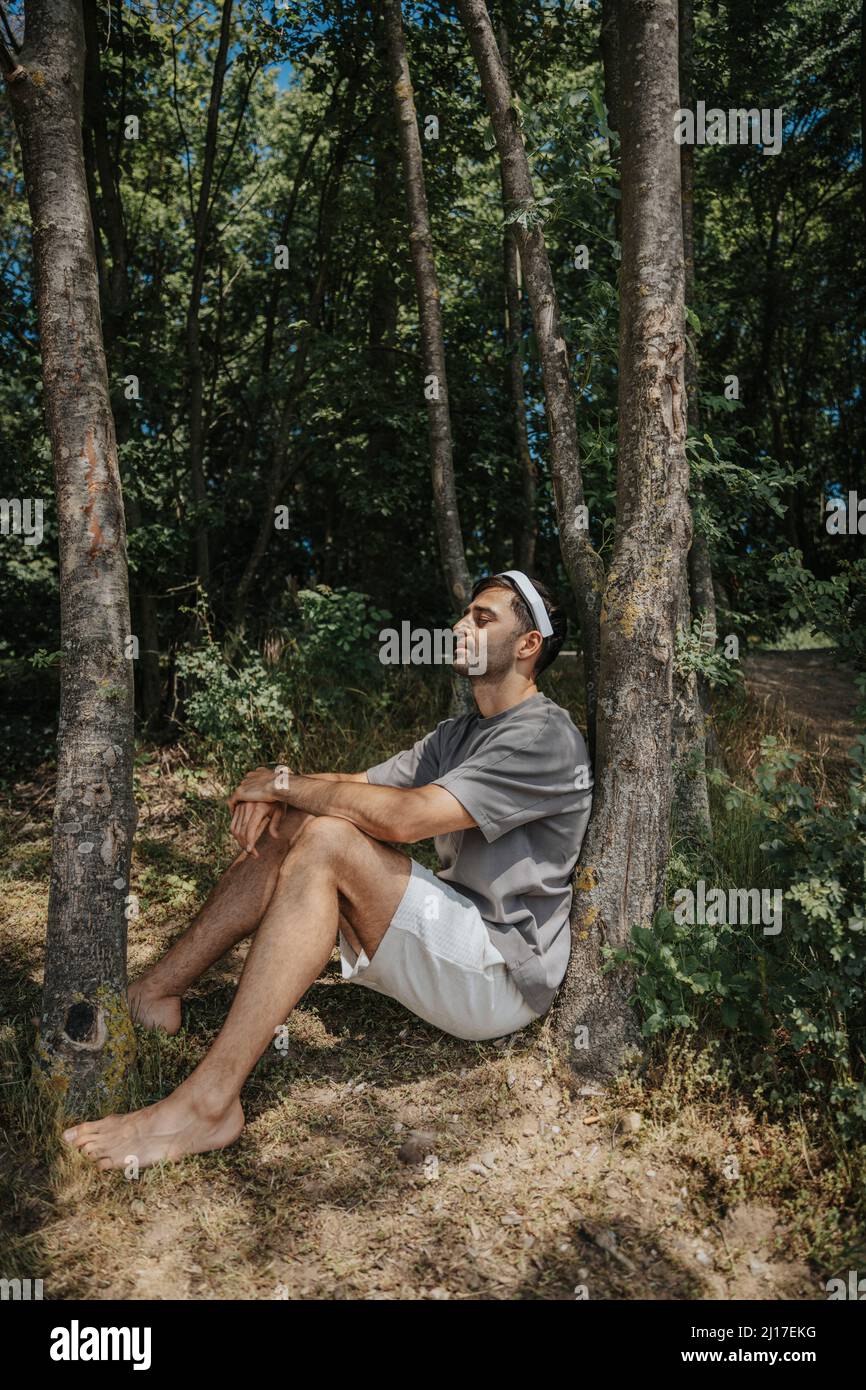 Man sitting amidst trees in nature Stock Photo - Alamy