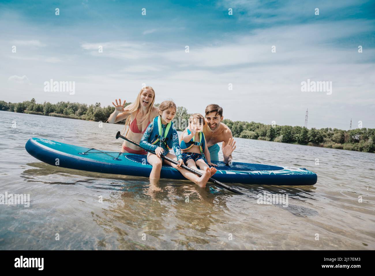 Cheerful family with paddleboard in lake on weekend Stock Photo - Alamy