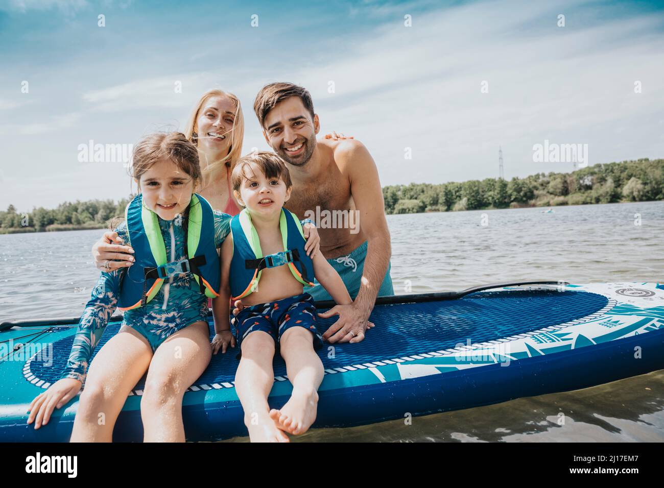 Children sitting on paddleboard in front of parents at weekend Stock ...