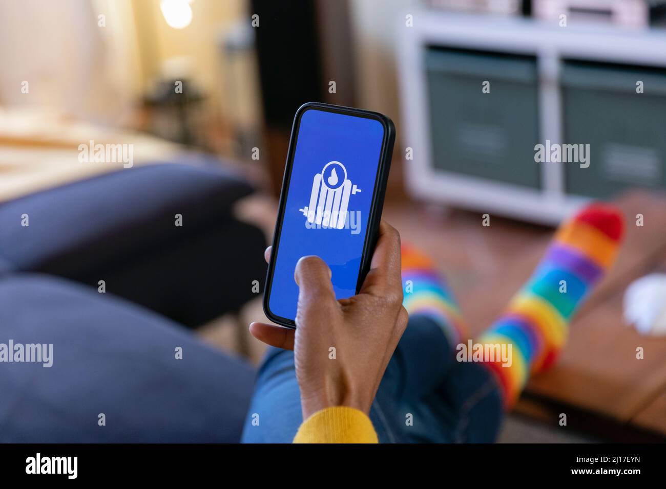 Woman's hand using mobile app in living room Stock Photo - Alamy
