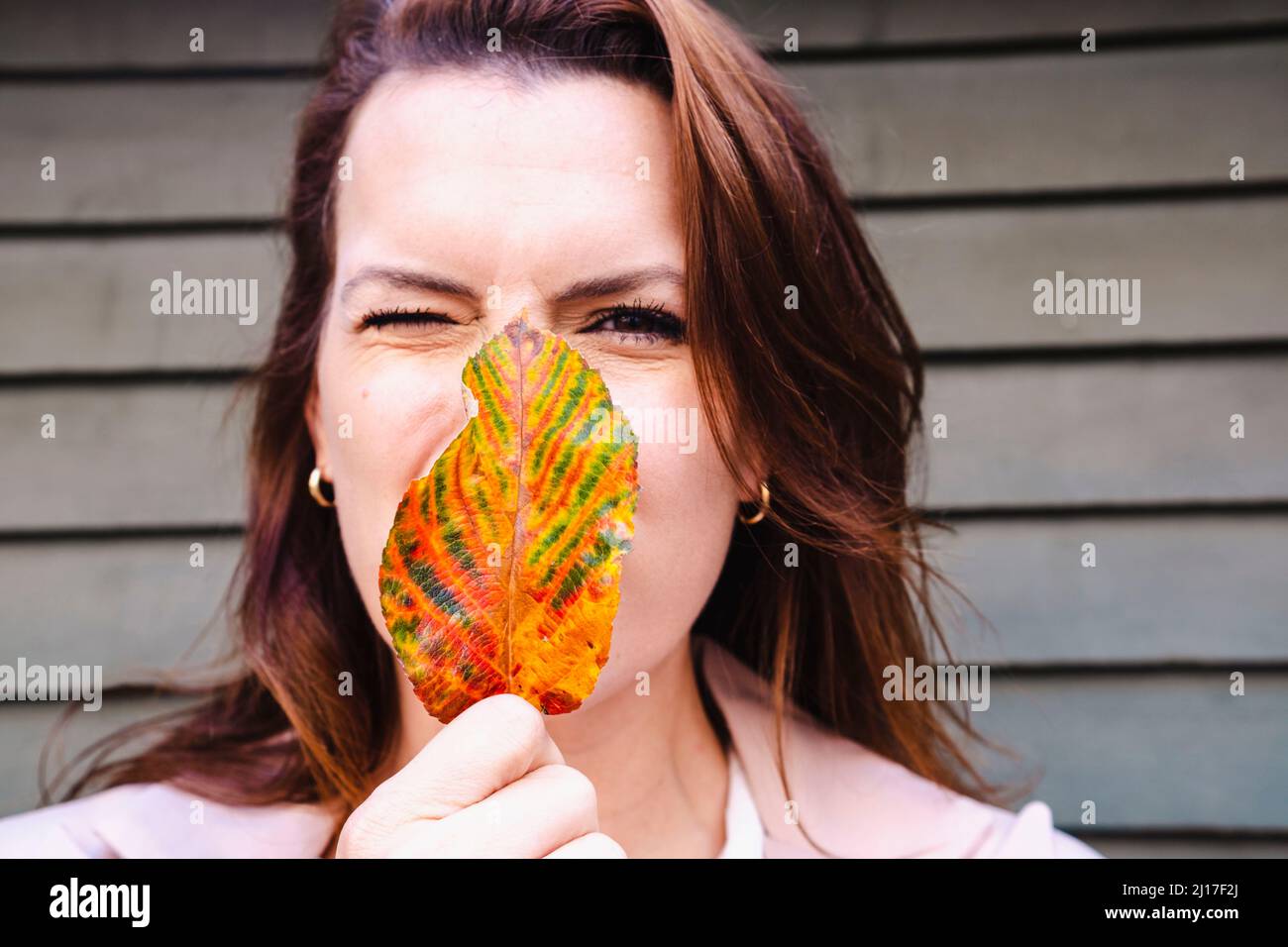 Woman covering mouth with autumn leaf Stock Photo - Alamy