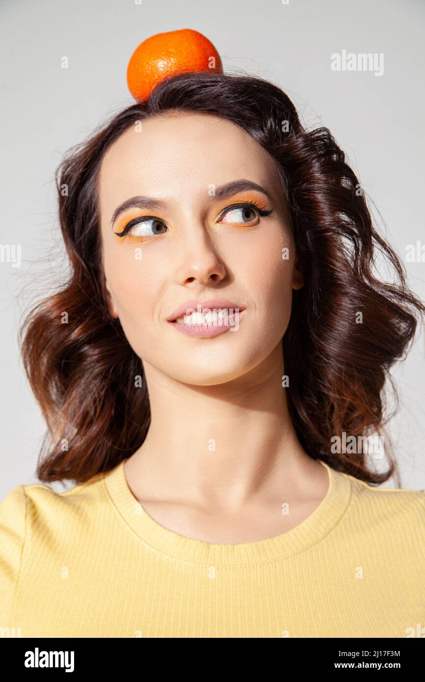 Woman balancing tangerine on head against white background Stock Photo ...