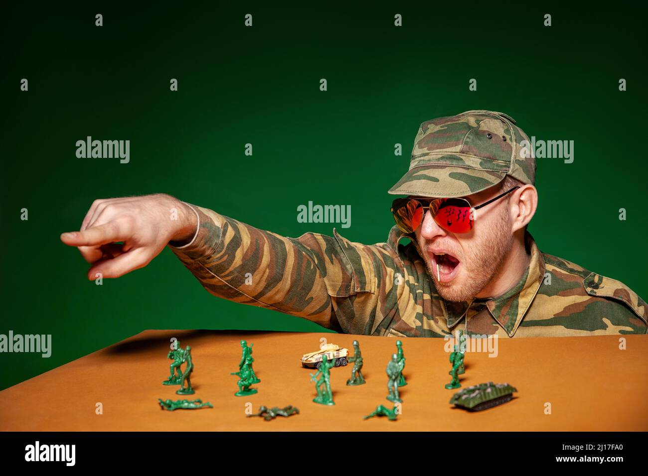 Army soldier playing with figurine toys against green background Stock ...