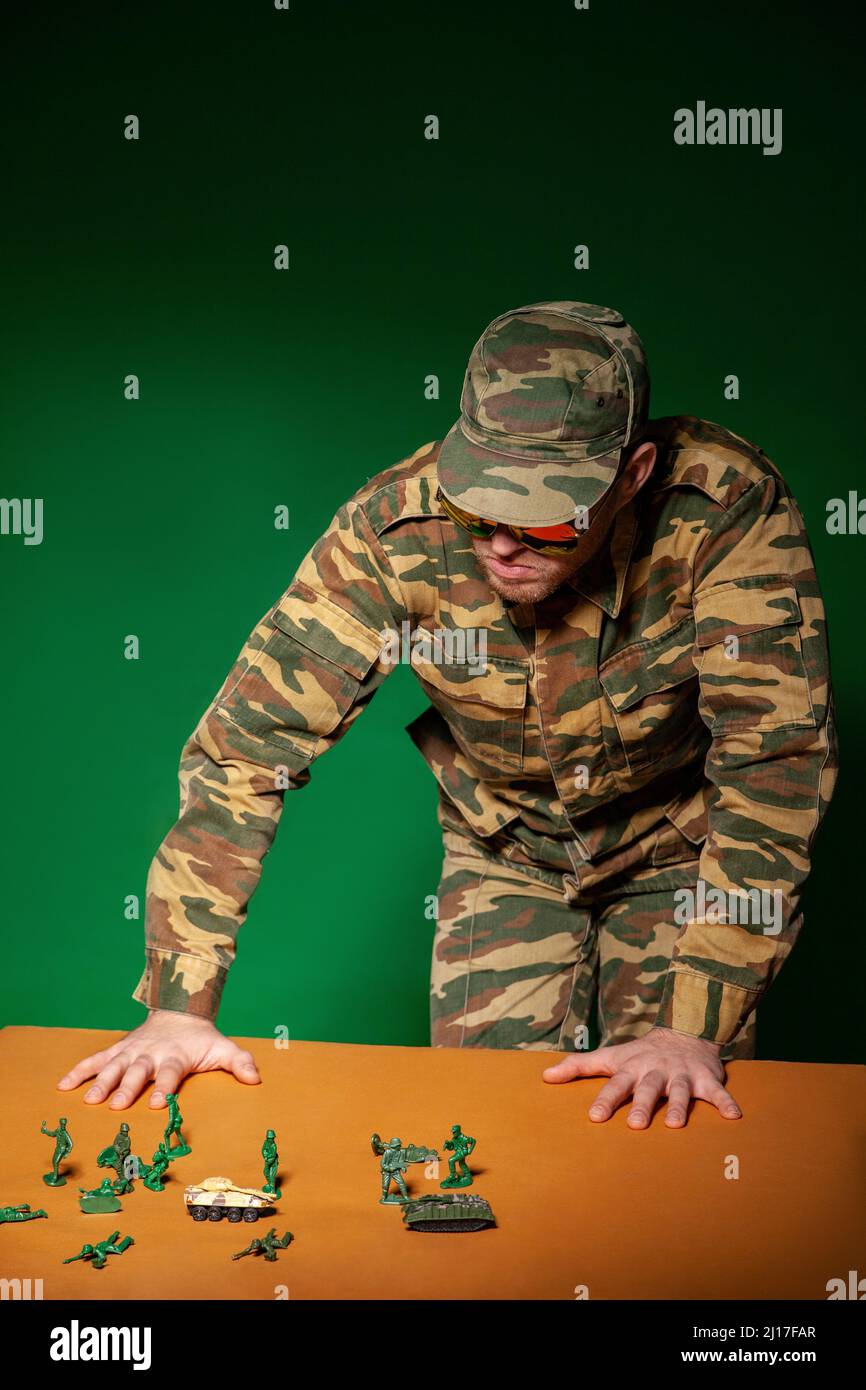Young military soldier with army figurine toys standing by table ...