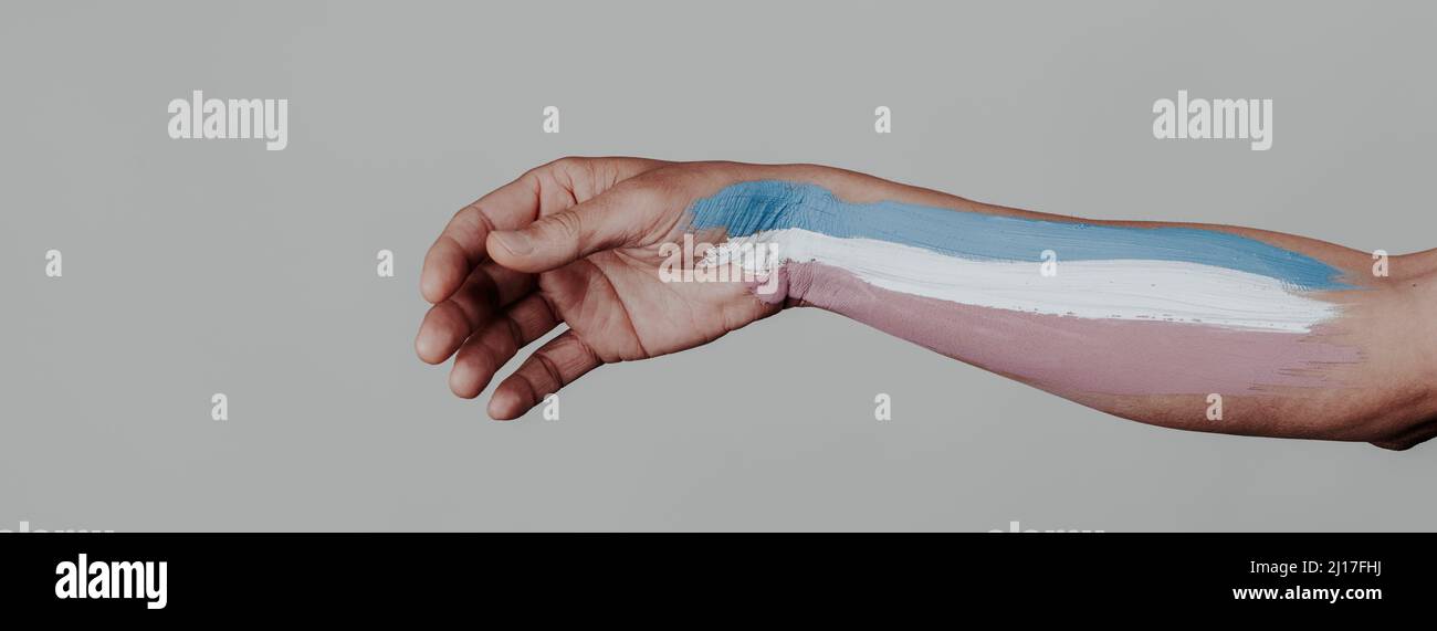 the arm of a young caucasian person with the transgender pride flag ...