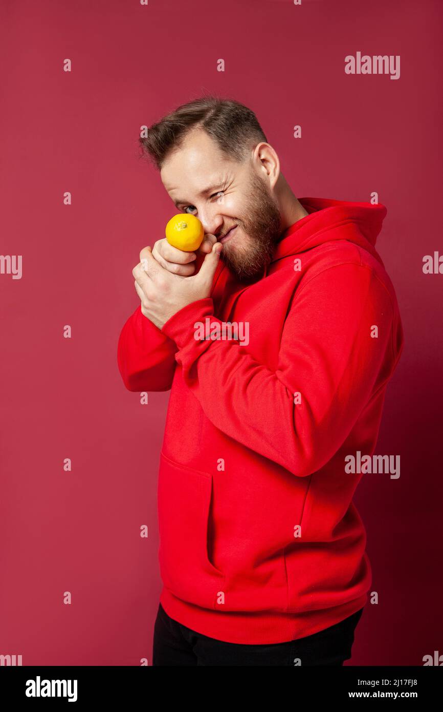 Playful man with lemon fruit by red background Stock Photo - Alamy