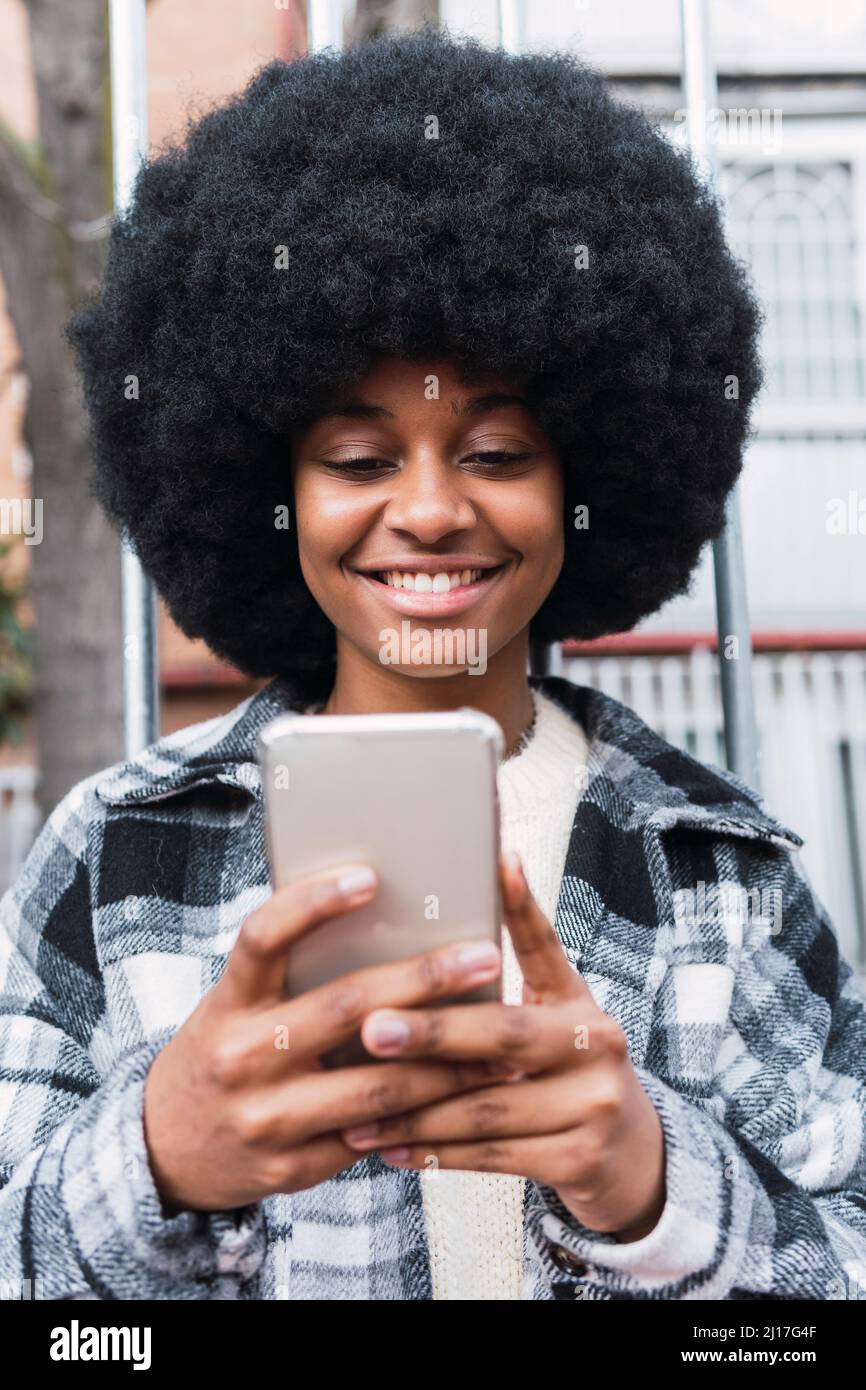 Happy afro woman text messaging through smart phone Stock Photo - Alamy