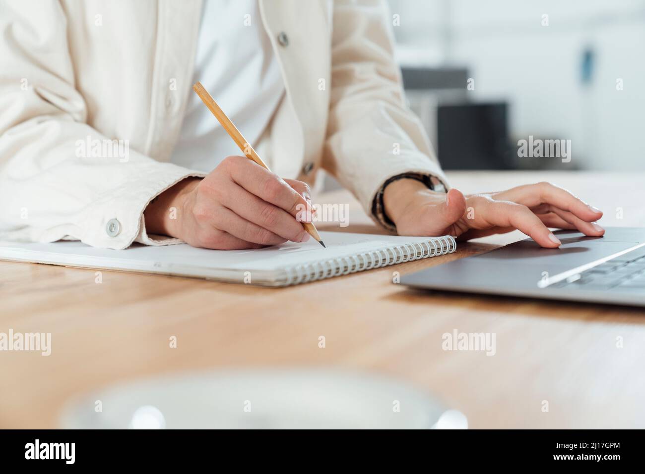 Entrepreneur writing on notepad and using laptop at workshop Stock ...