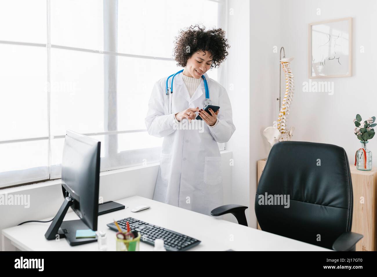 Doctor using mobile phone standing in medical office Stock Photo - Alamy