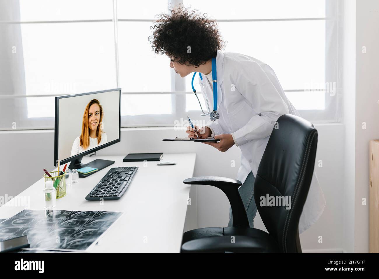 Doctor discussing with patient through video call at medical clinic ...