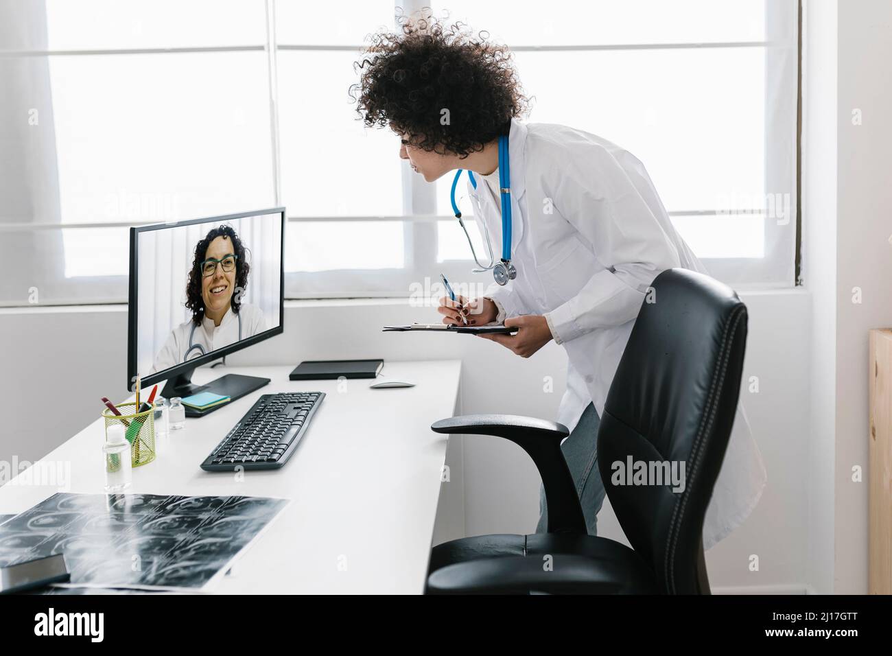 Doctor on video call with colleague through desktop PC at medical ...
