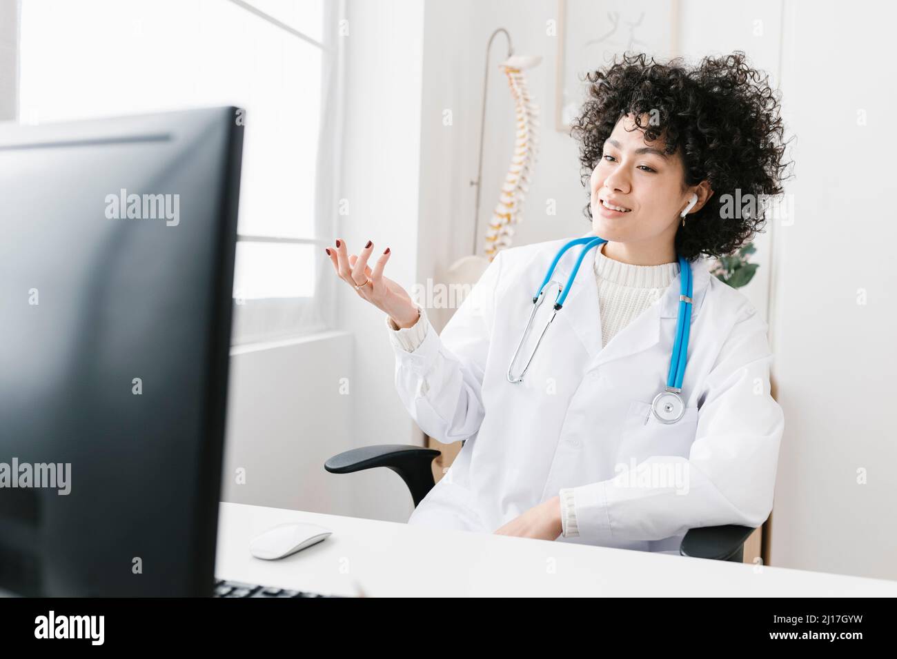 Doctor wearing in-ear headphones discussing on video call at medical ...