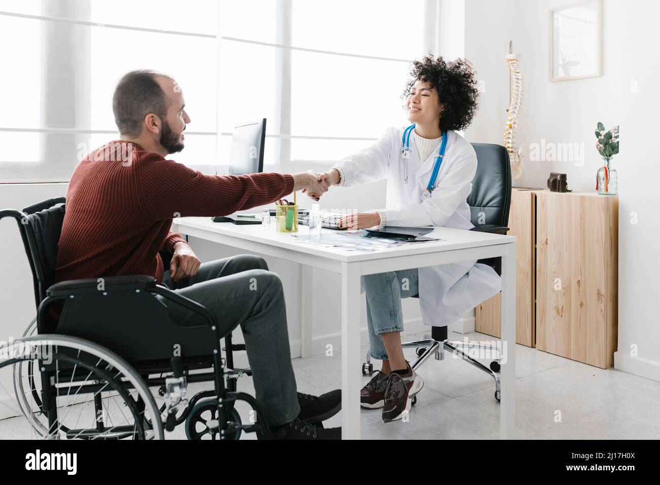 Disable patient sitting in wheelchair shaking hand with doctor at ...