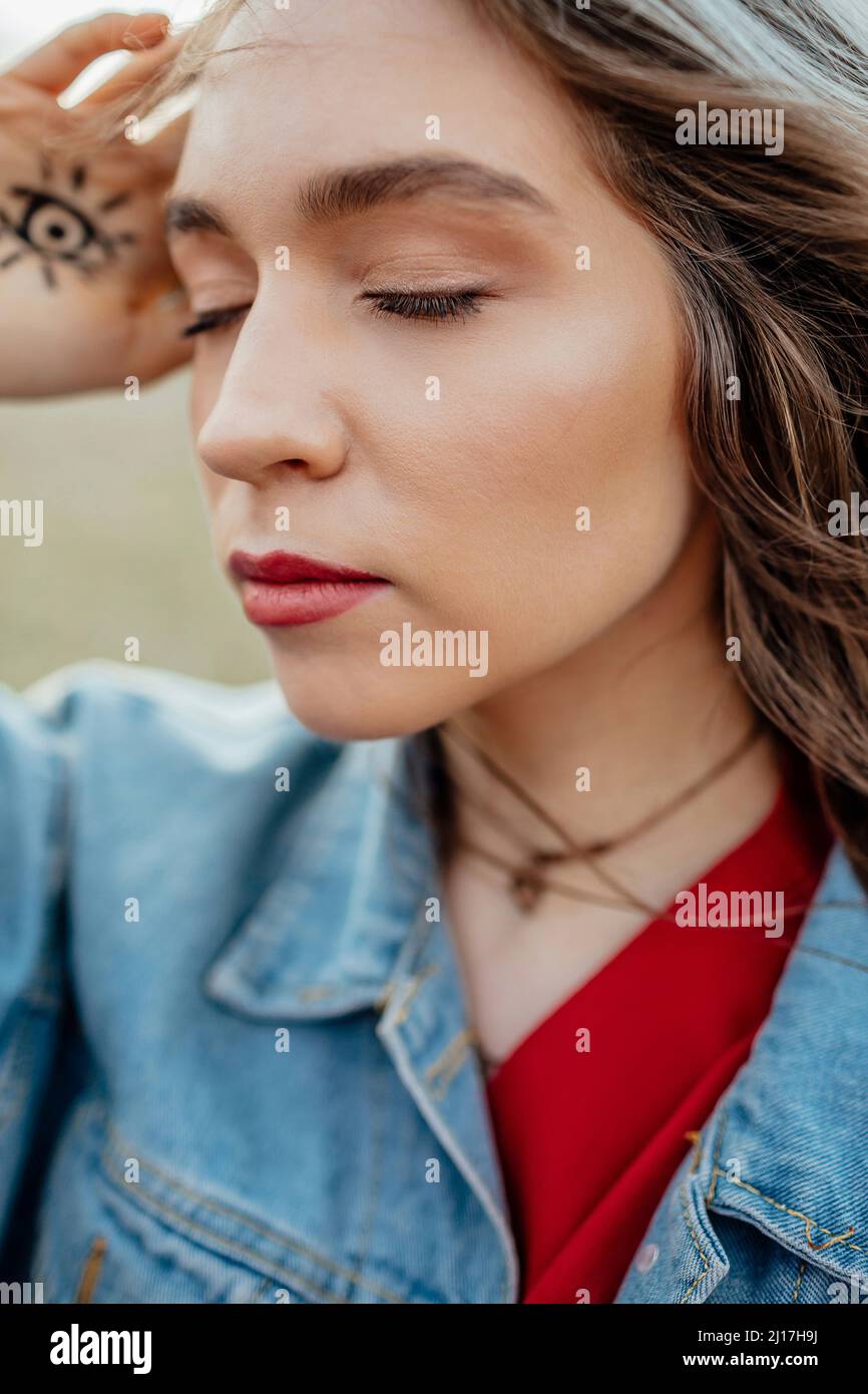 Woman with eyes closed wearing denim jacket Stock Photo - Alamy