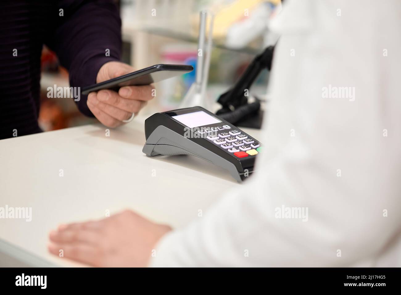 Customer making contactless payment through smart phone at checkout ...