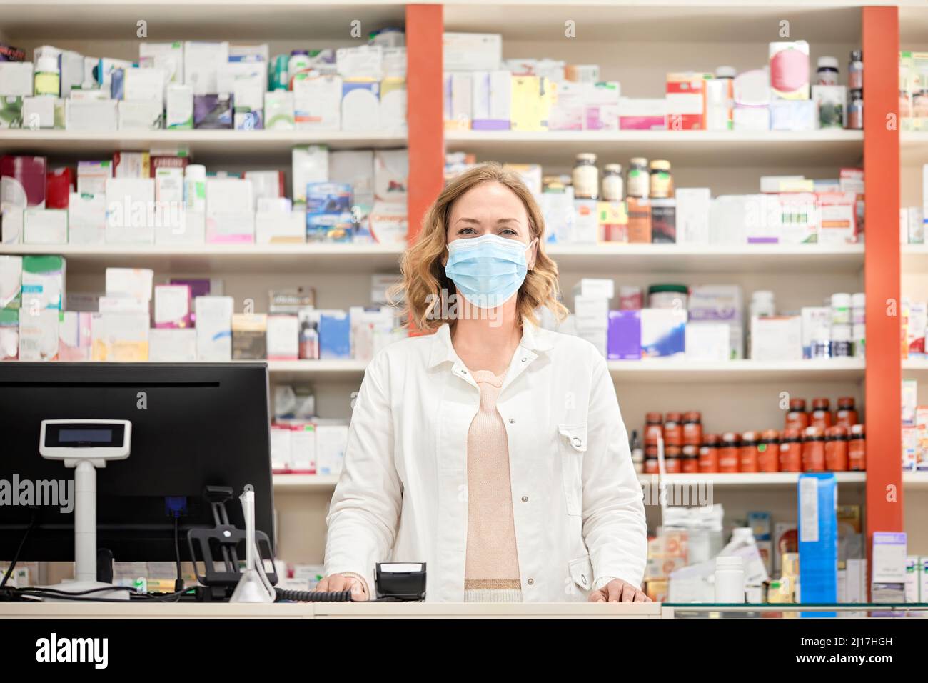 Female pharmacist wearing protective face mask standing at checkout in ...