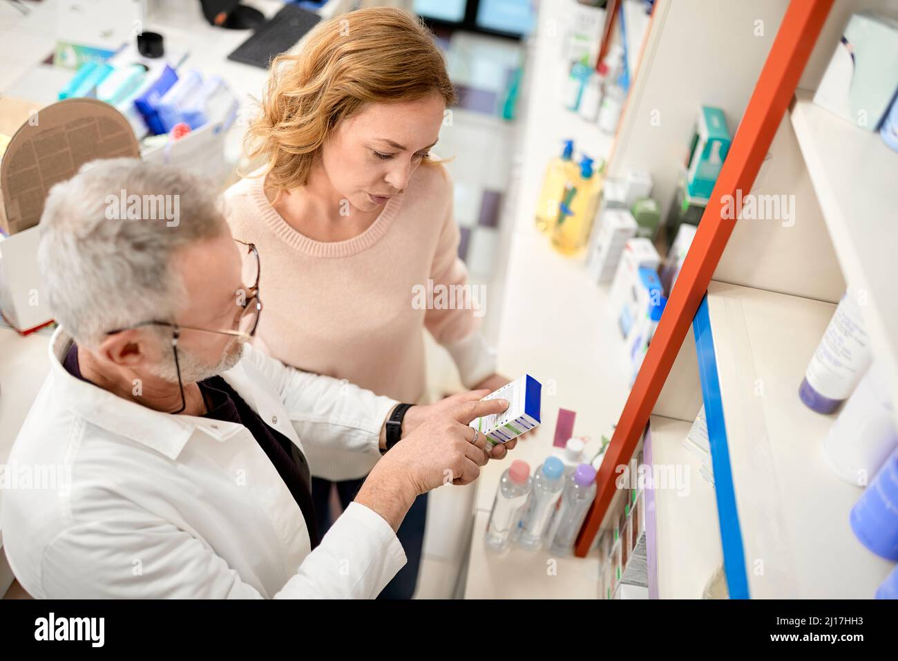 Pharmacist helping customer reading instruction on medicine box at ...