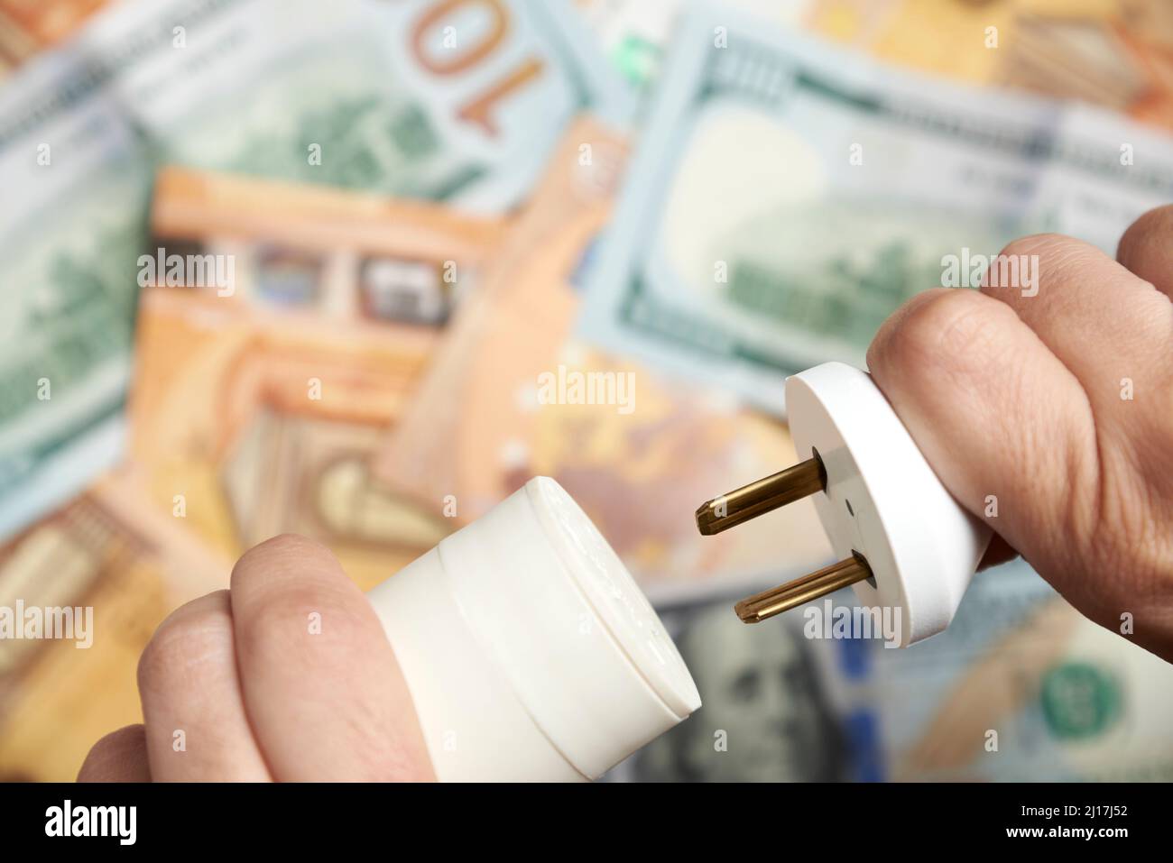 Hands plugging or unplugging a socket against a background of dollar ...