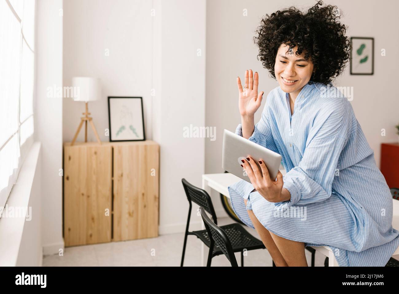Happy woman waving hand on video call through tablet PC at home Stock ...