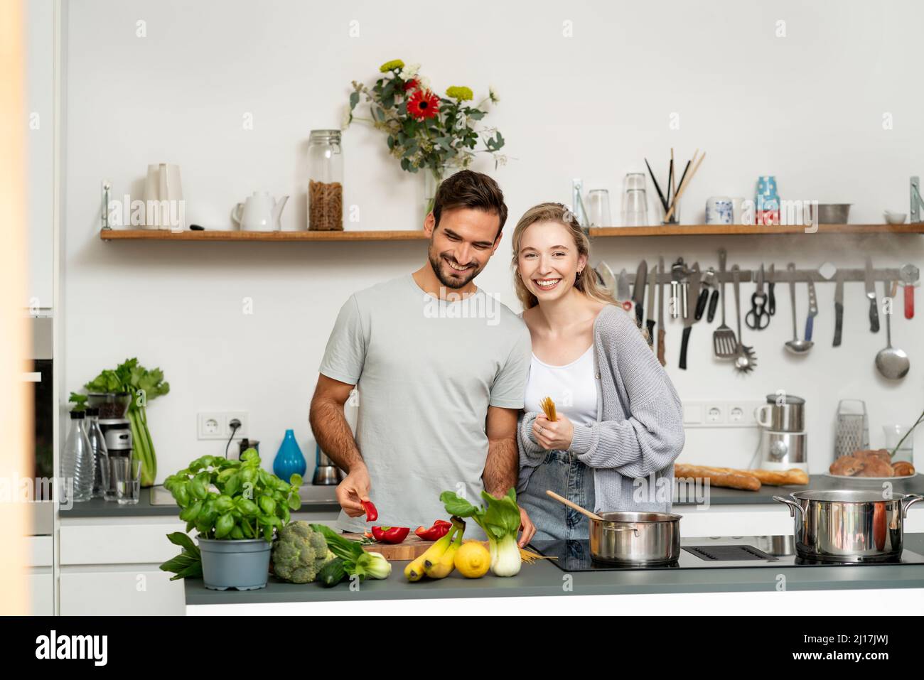 Happy girlfriend and boyfriend preparing food in kitchen Stock Photo ...