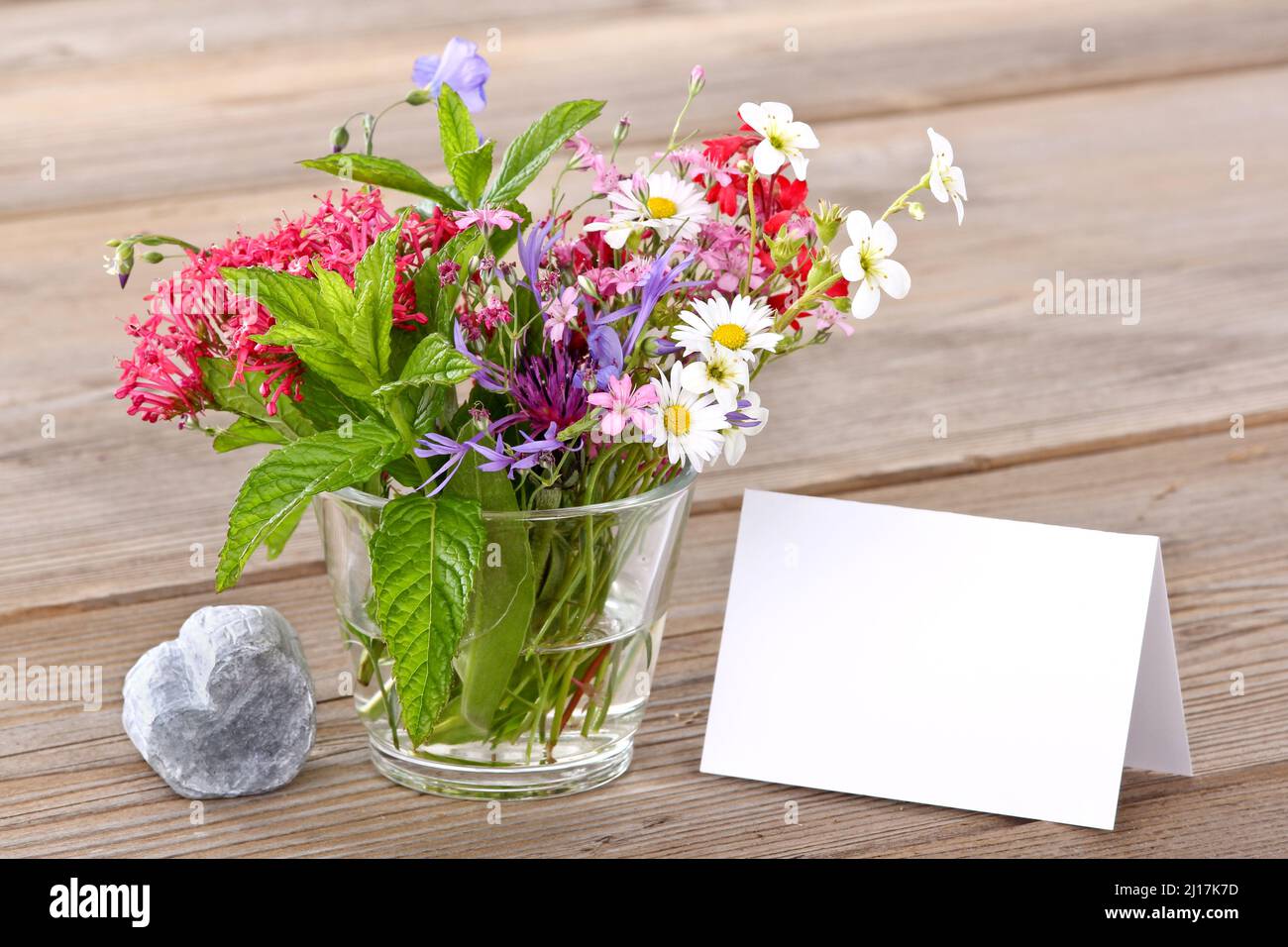 Heart-shaped stone with a small bouquet of flowers Stock Photo - Alamy