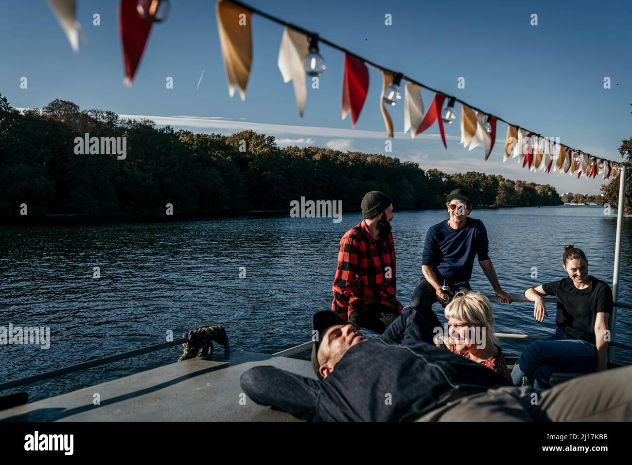 Smiling friends talking with each other sitting on boat deck Stock ...